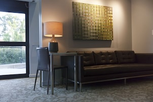 Uma sala de estar moderna com um sofá, uma mesa com abajur e um quadro abstrato grande na parede.