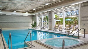 Piscina interna com hidromassagem, espreguiçadeiras e janelas amplas.