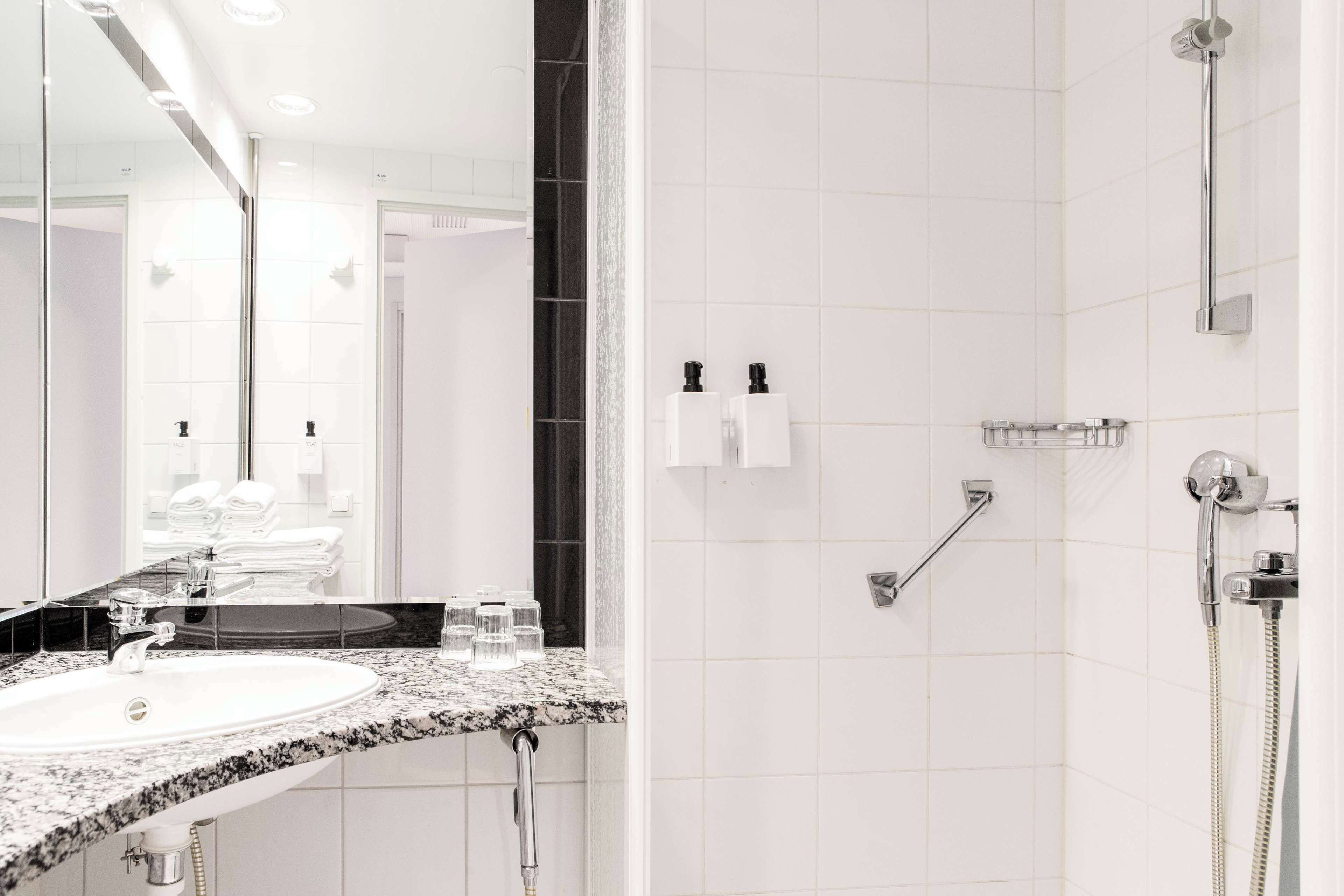 Uma casa de banho moderna com uma pia branca, um espelho grande e uma zona de duche.
