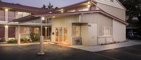 Um motel de dois andares com entrada coberta e estacionamento.