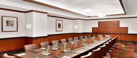 Uma sala de conferência com uma mesa comprida, várias cadeiras e obras de arte emolduradas nas paredes.