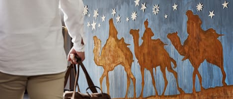 Uma pessoa caminhando perto de um muro com céu estrelado e silhuetas de camelos.