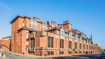 Um edifício grande de tijolos, com várias janelas e uma placa com a inscrição 'Crown Plaza Chester'.