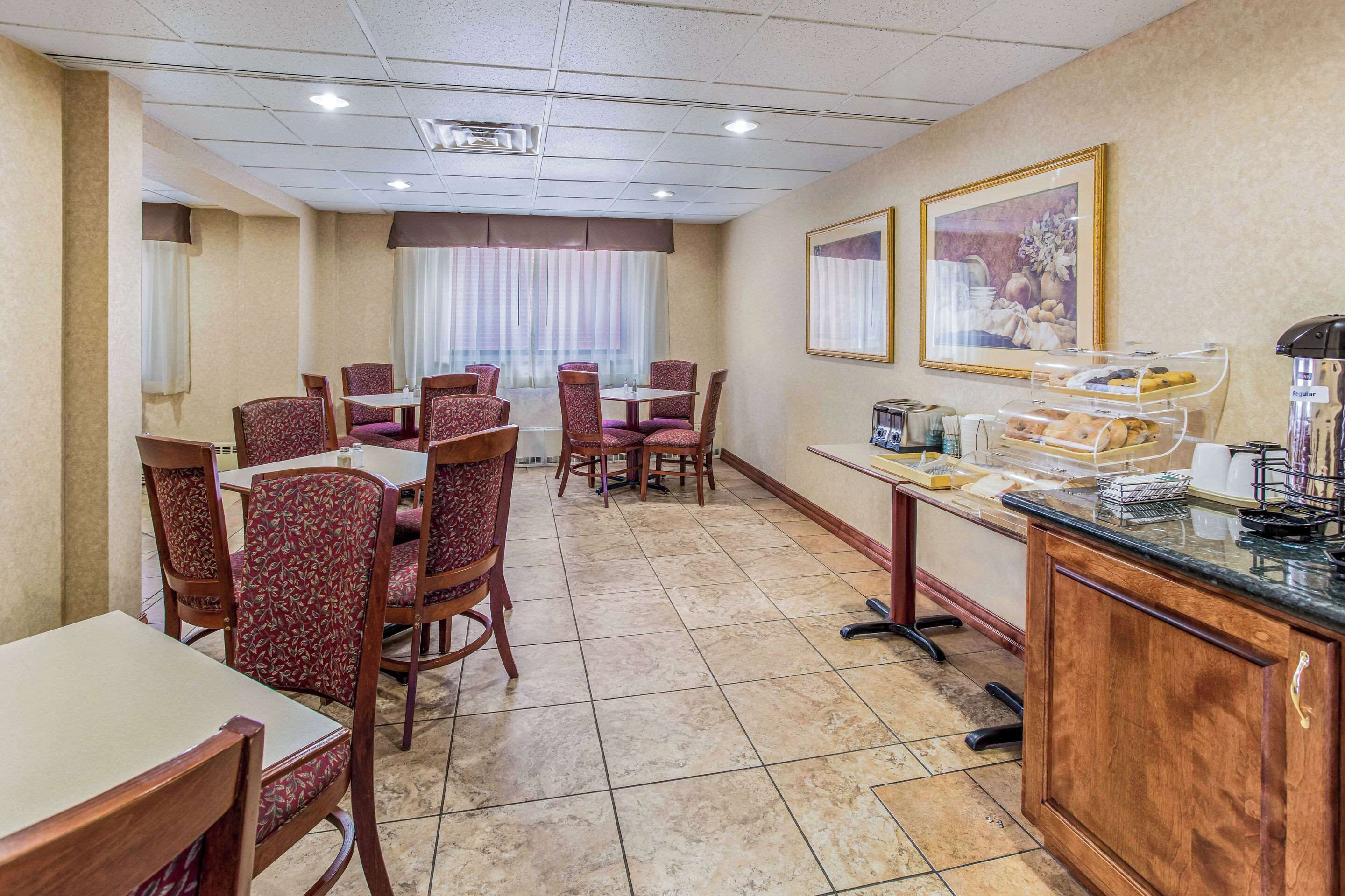 Uma sala de jantar de hotel com uma mesa comprida e cadeiras, um canto de café e quadros nas paredes.