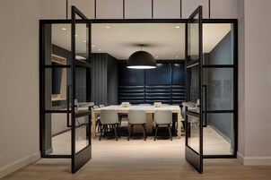 Uma sala de jantar moderna com divisória de vidro, mesa central e cadeiras.