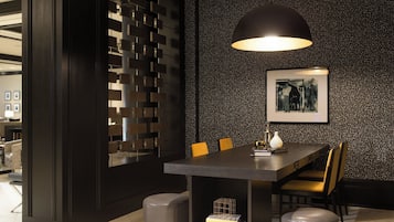 Uma sala de jantar moderna com mesa de madeira escura, cadeiras e uma luminária pendente.
