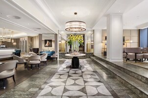 Um saguão de hotel com uma mesa redonda central, área de estar e um lustre.