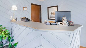 Um balcão de recepção com design moderno, uma luminária, obras de arte emolduradas e um lanterna decorativa.