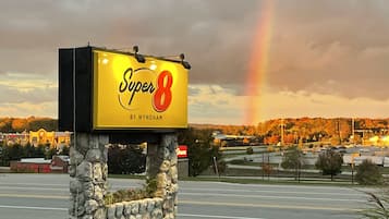Placa Super 8 by Wyndham com base de pedra, com um estacionamento e um arco-íris ao fundo.