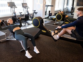 Uma academia com equipamentos de cardio, esteira e remo.