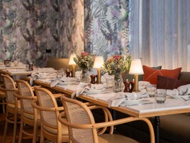 Restaurante com mesas de madeira, cadeiras de vime e centros de mesa florais.