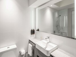 Casa de banho moderna com sanita, lavatório e chuveiro.