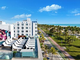 Terraço de hotel com espreguiçadeiras, piscina e vista para a praia e o oceano.