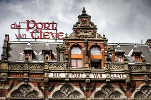 Um edifício histórico com detalhes arquitetônicos elaborados, incluindo uma placa de destaque com a inscrição 'Die Port van Cleve'.