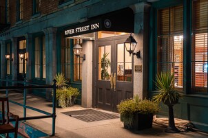 Exterior do River Street Inn, com porta escura, plantas em vasos e guarda-corrimão de metal.