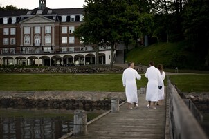 Um cais de madeira que leva a um edifício com uma grande janela e uma parede de pedra.