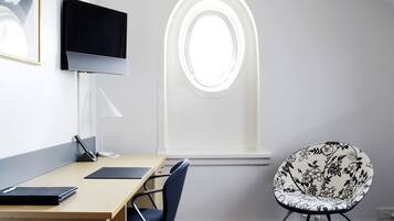 Quarto moderno com escrivaninha, cadeira e televisão fixada na parede.