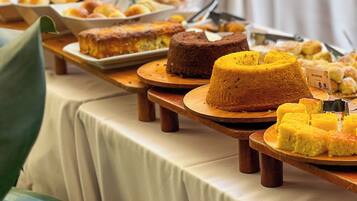 Uma mesa de buffet com diversos alimentos e um bolo em suportes de madeira.