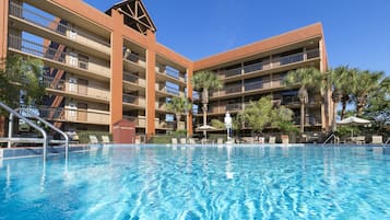 Um hotel com piscina, várias varandas e palmeiras.