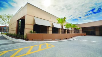 Um edifício moderno com telhado plano, amplas janelas e um estacionamento com setas indicativas.
