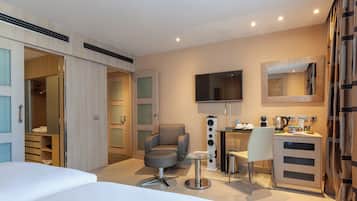 Quarto de hotel moderno com uma cama, uma escrivaninha com computador, uma cadeira, televisão e guarda-roupa.