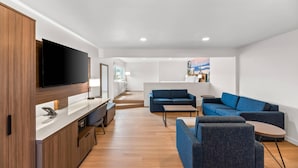 Uma sala de estar moderna com televisão de tela plana, armários de madeira, um sofá e uma mesa de centro.