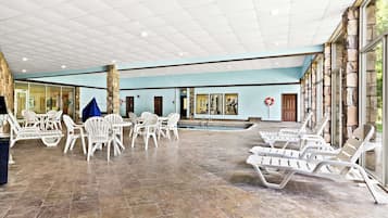 Amplo espaço interno com piscina, espreguiçadeiras e mesas.