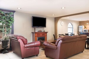 Sala de estar com lareira, sofás de couro, televisão e espaço para refeições.