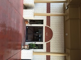 Entrada de um prédio com piso de azulejos, porta de vidro e o número '963' na parede.