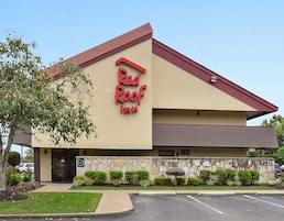 Um Red Roof Inn com fachada de pedra, telhado vermelho e estacionamento.