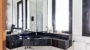 Um banheiro moderno com uma pia de mármore preto, um espelho grande e um porta-toalhas.