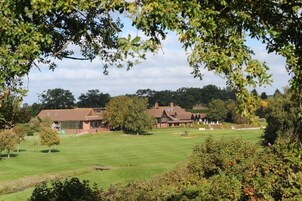 Um campo de golfe com dois edifícios, um com uma grande janela e outro com uma chaminé.