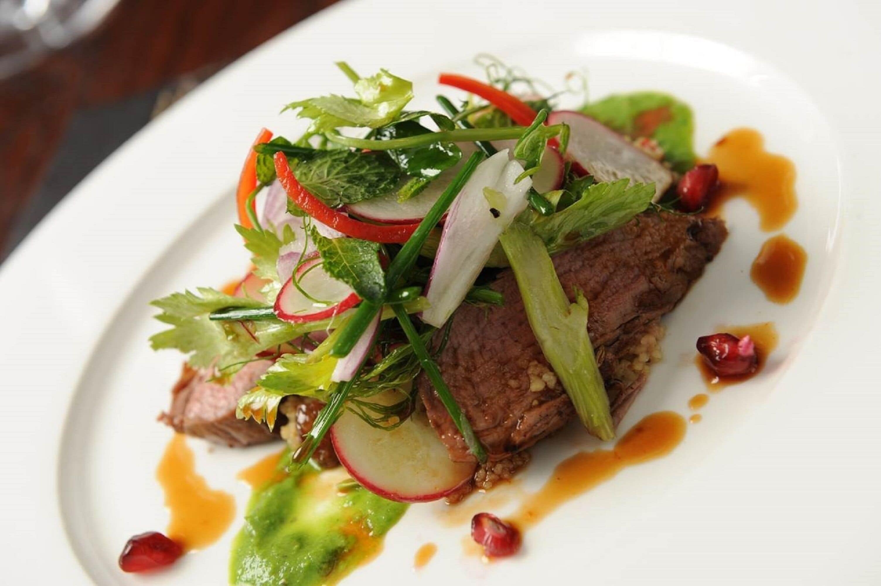 Prato de comida com carne, legumes e molho.
