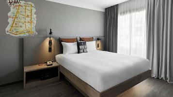 Quarto de hotel moderno com uma cama grande, um quadro de mapa na parede, uma mesa de cabeceira com abajur e uma janela com cortinas.