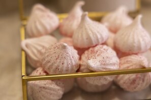 Close-up de marshmallows cor-de-rosa sobre uma grade dourada.
