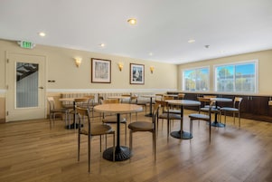 Um restaurante com várias mesas e cadeiras, uma escada e obras de arte emolduradas nas paredes.