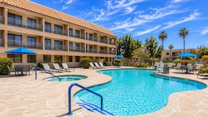 Um hotel com piscina, espreguiçadeiras e guarda-sóis.