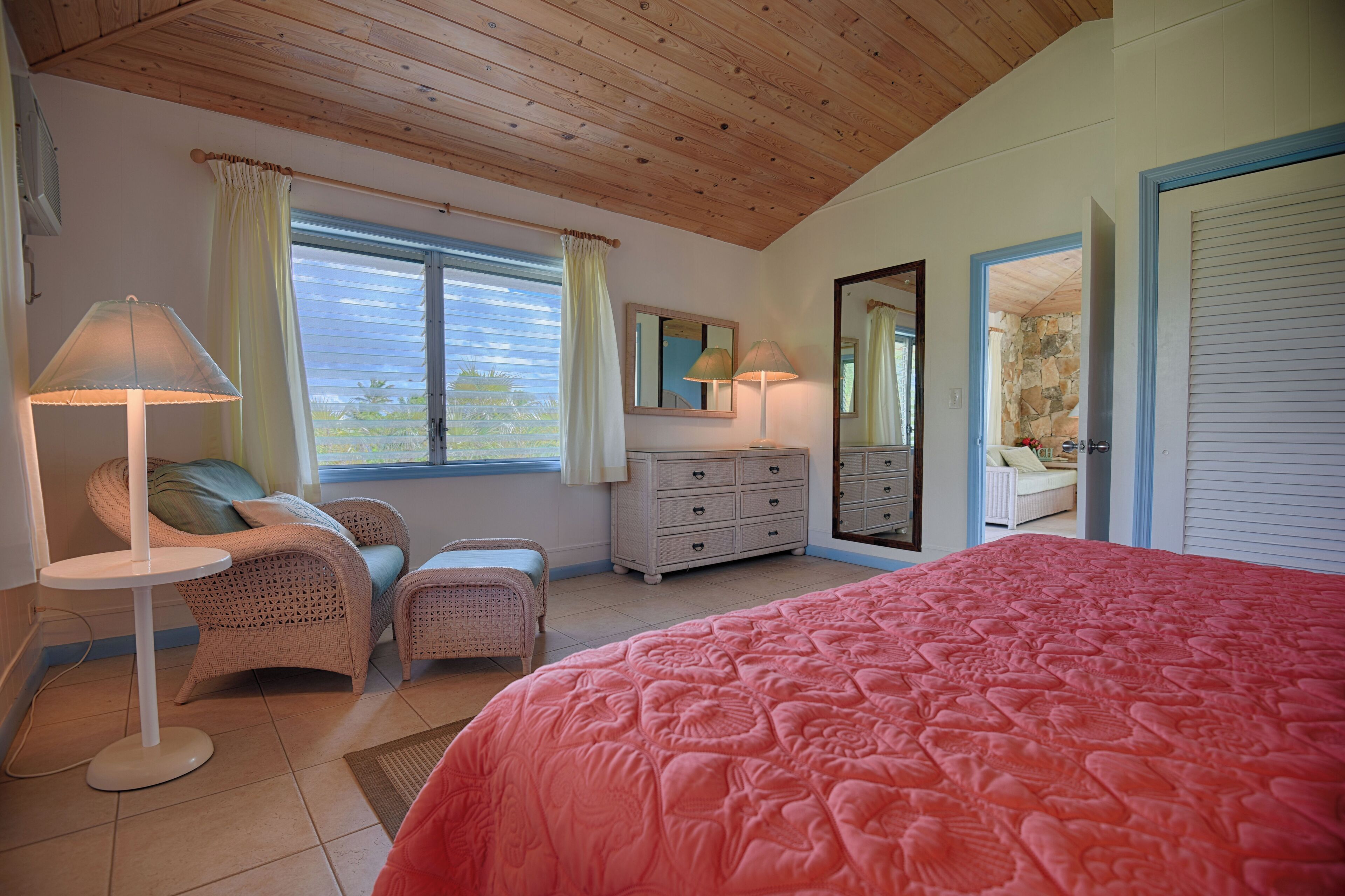 Quarto com cama grande, duas cadeiras, cômoda e espelho.