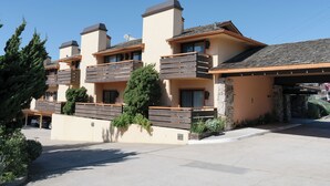 Um edifício residencial de vários andares com varandas, fachada de pedra e céu claro.