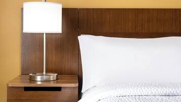 Cama bem arrumada com travesseiro branco e cabeceira de madeira.