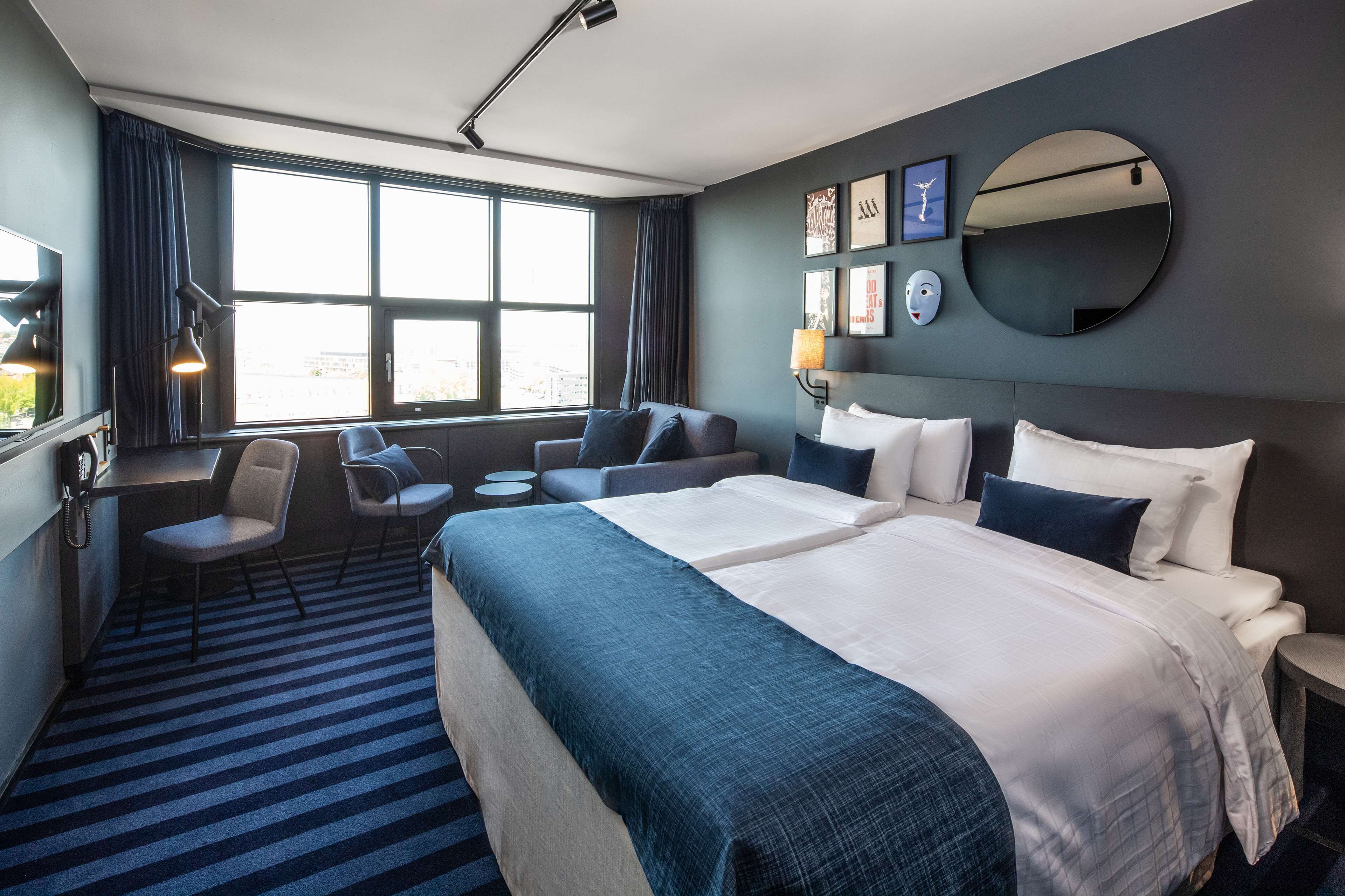 Quarto de hotel moderno com uma cama grande, uma escrivaninha e um espaço de estar.