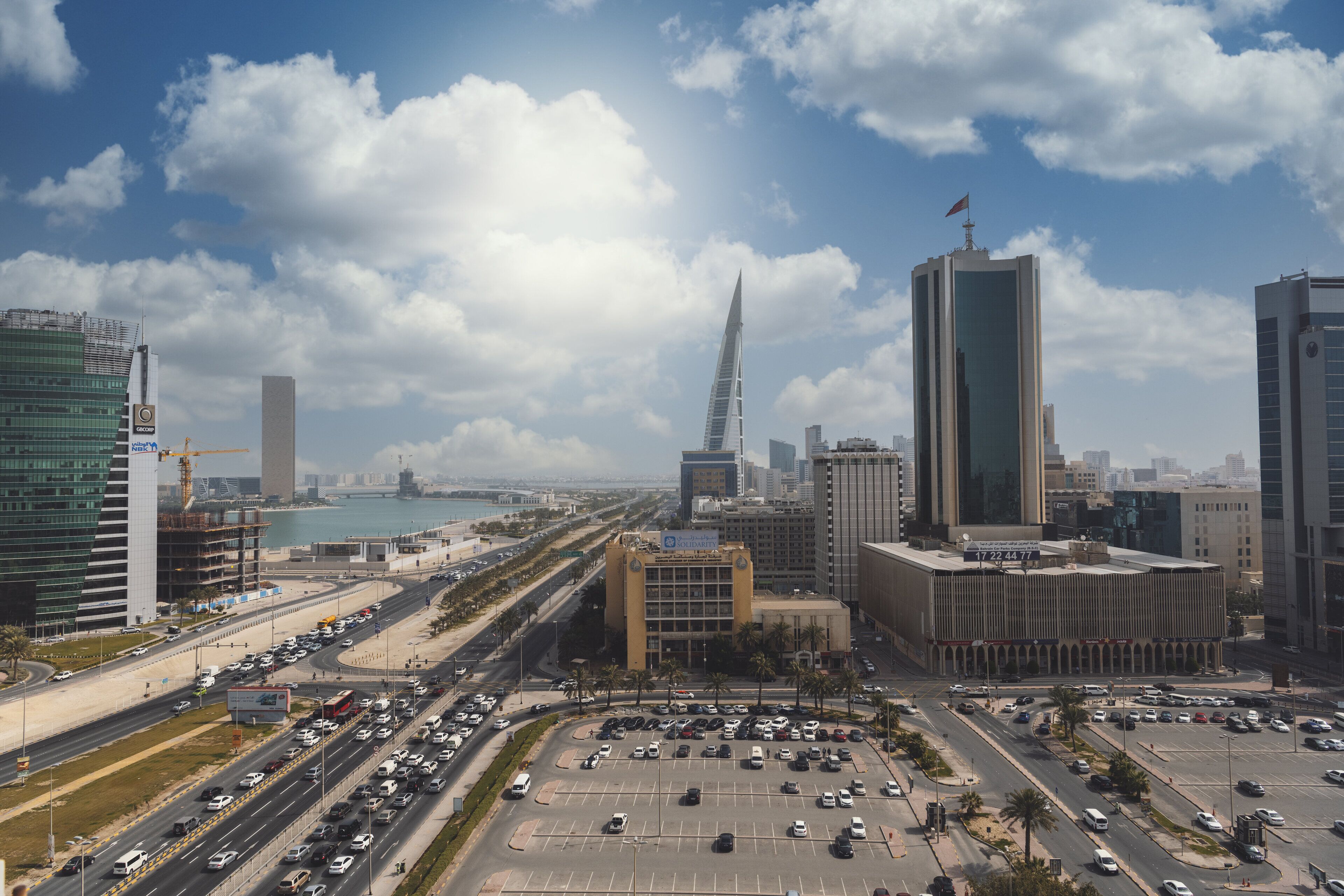 Paisagem urbana com edifícios modernos, um arranha-céu imponente e um cruzamento movimentado.