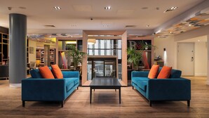 Um hall amplo com dois sofás azuis, uma mesa de centro e piso de madeira.