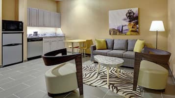 Um espaço de estar compacto com cozinha compacta, um conjunto de sofás, uma mesa de jantar e um tapete com padrão de zebra.