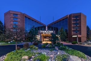 Um hotel DoubleTree by Hilton com fachada simétrica, grandes janelas e área de entrada ajardinada.