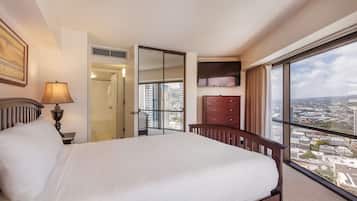Quarto de hotel com uma cama grande, televisão, cômoda e vista da cidade.