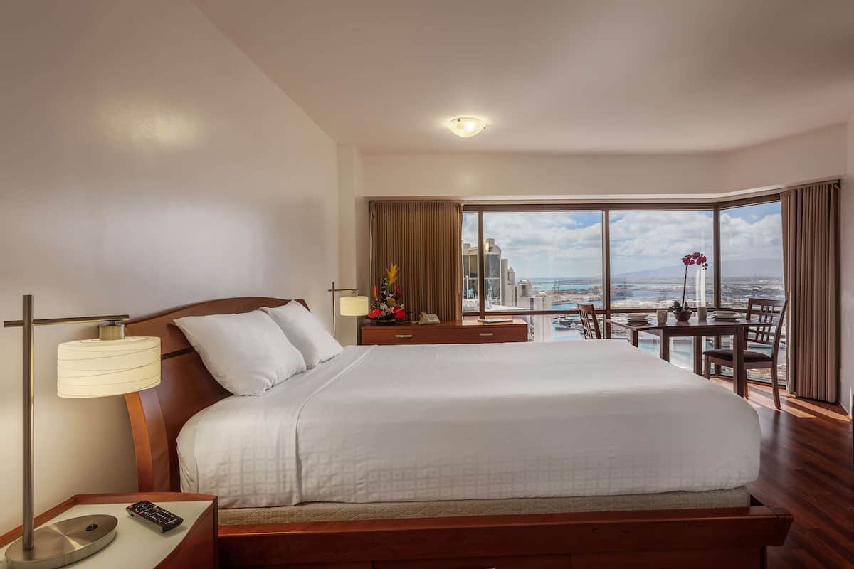Quarto de hotel com uma cama grande, uma escrivaninha e vista para a cidade.
