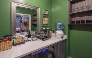 Uma cozinha compacta equipada com cafeteira, chaleira, liquidificador e bebedouro.