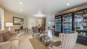Um hall de hotel moderno com assentos, área de refeições e um refrigerador abastecido com bebidas.