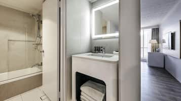 Uma casa de banho moderna com chuveiro, pia e espelho.
